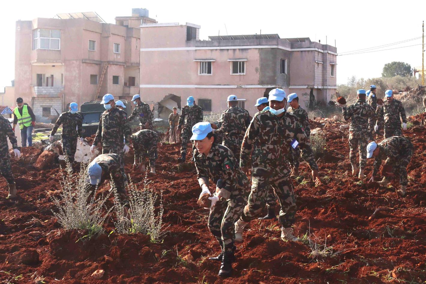 Nepalese peacekeepers assist Blida residents to prepare field for olive ...